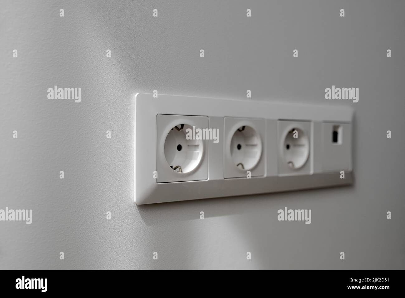 Blurred. White plastic walk-through switches and sockets on a white ...