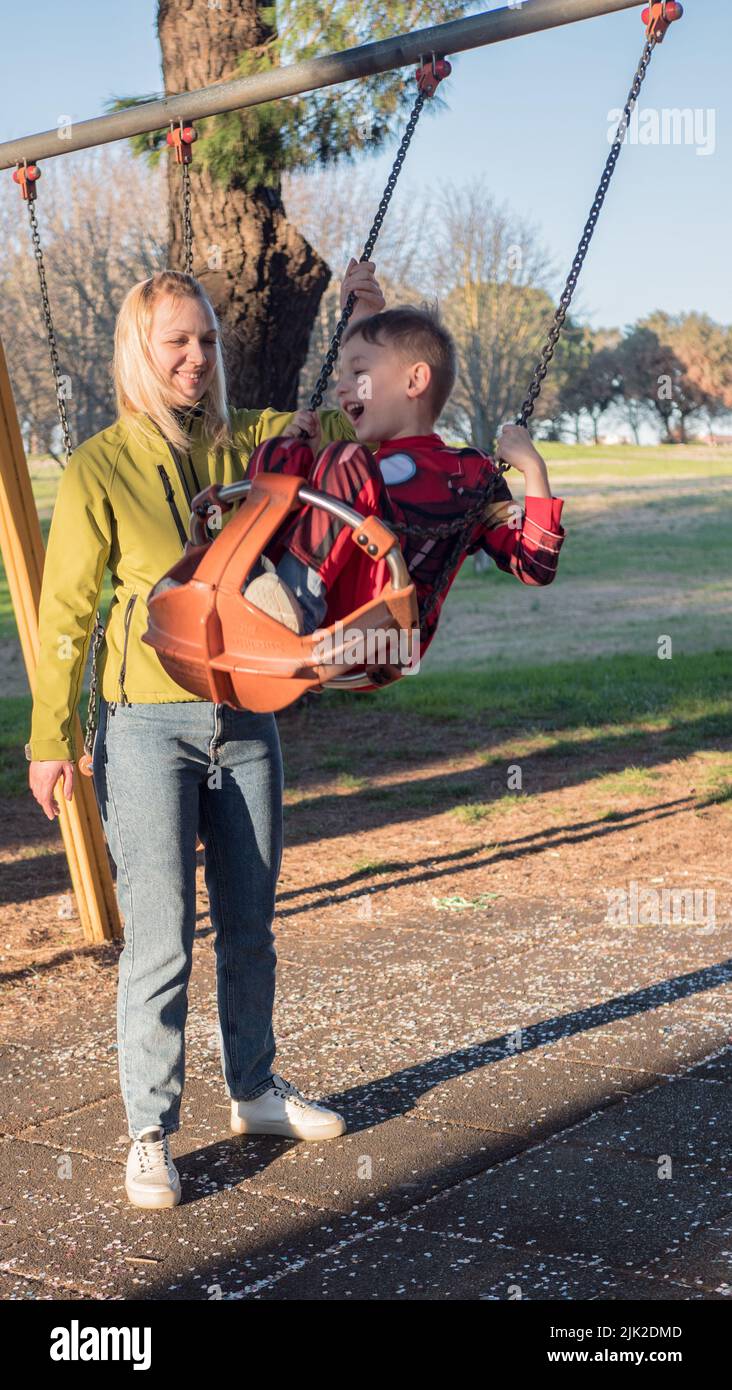 mother swings son on a swing in the park Stock Photo - Alamy