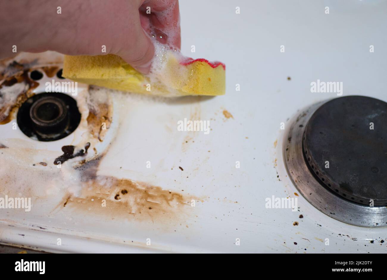 the man washes the working surface of the gas stove with a sponge and ...