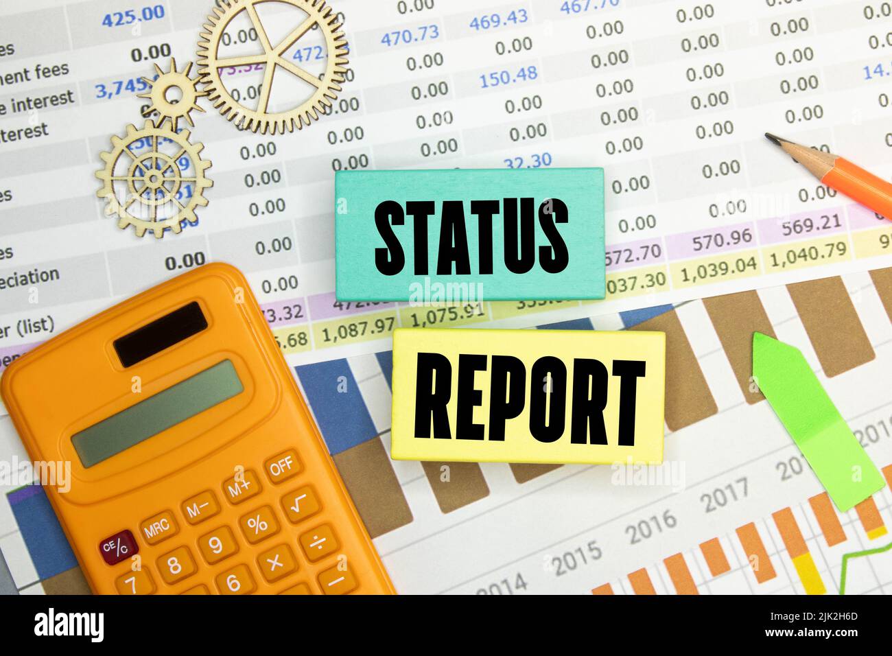 Top view of notebook and scrabble letters with text STATUS REPORT over ...