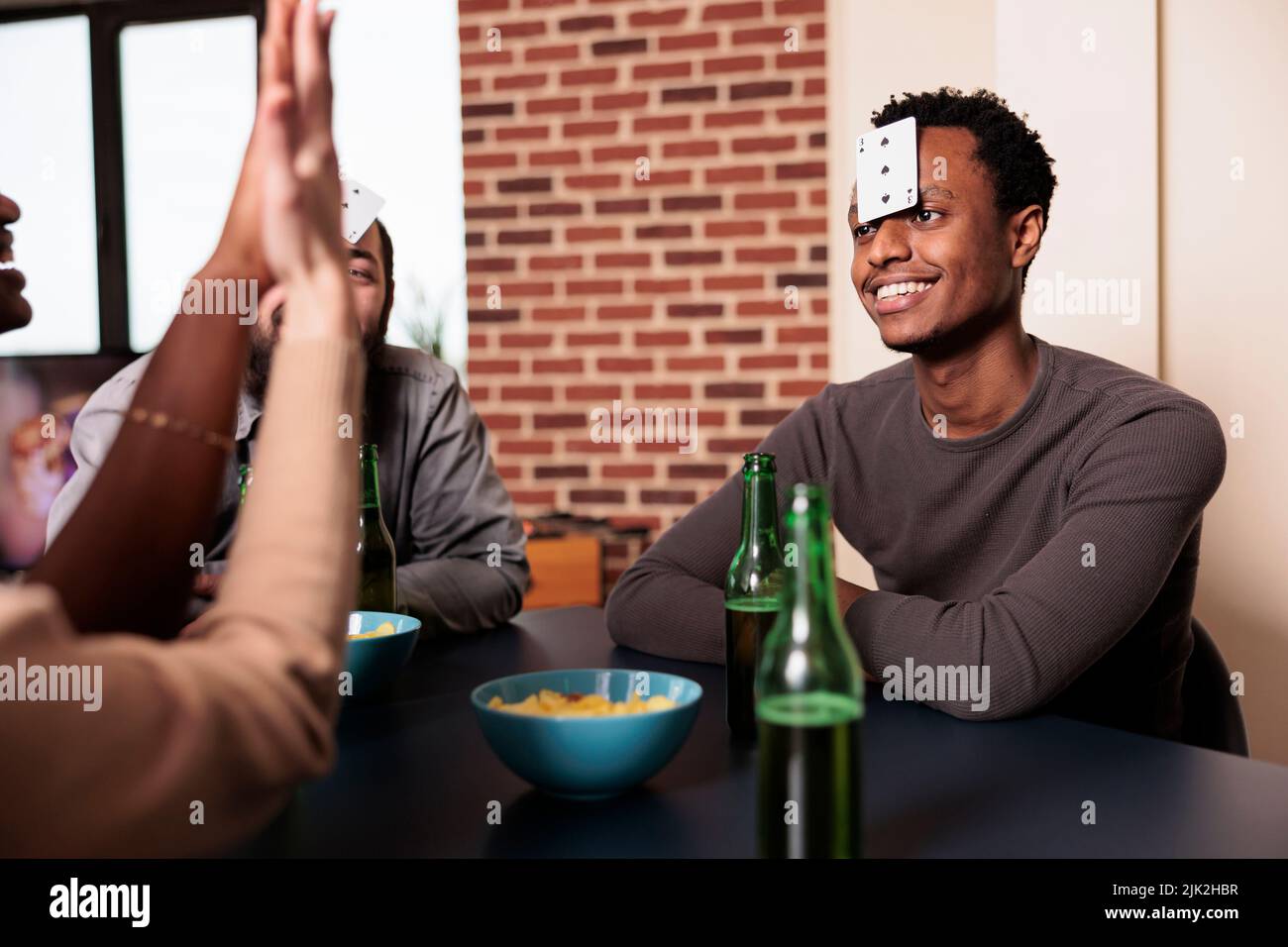 Happy diverse friends playing cards game together at home while ...