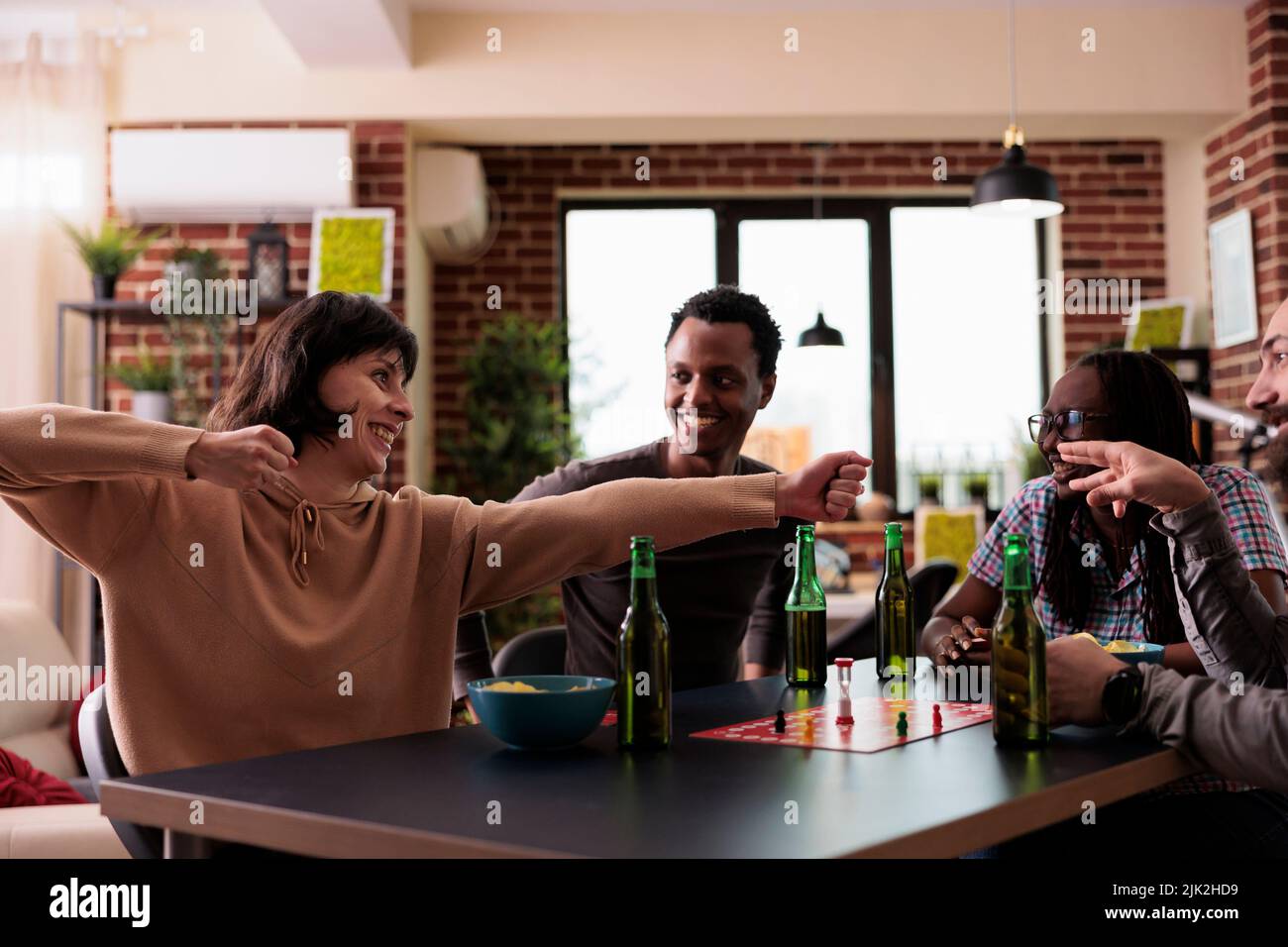 Happy playful woman acting childish while sitting with friends at home ...