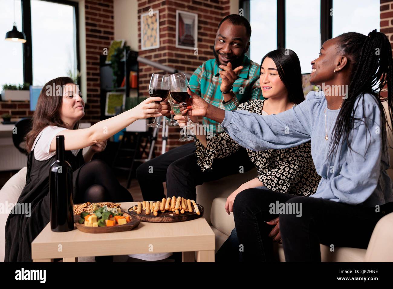 Joyful group of multiethnic people toasting at wine party while ...