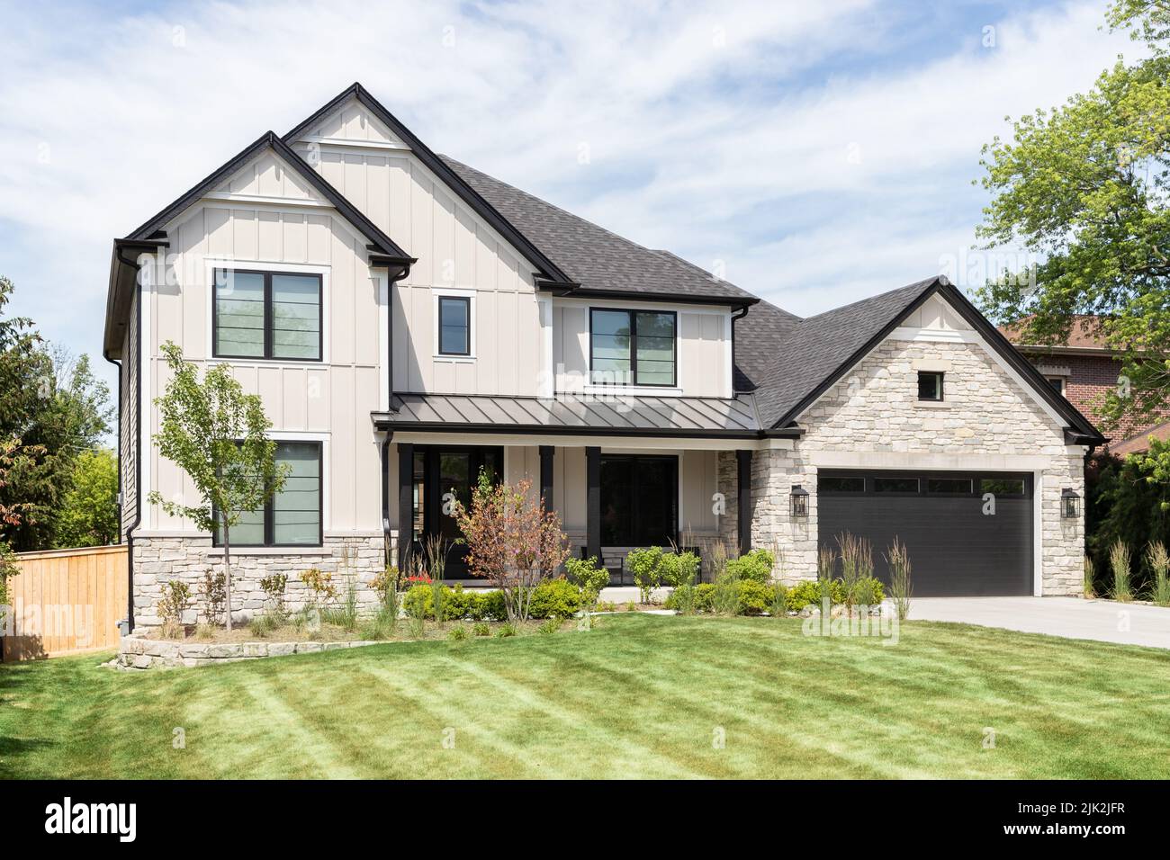 A tan modern farmhouse with a wainscoting siding, covered front porch ...