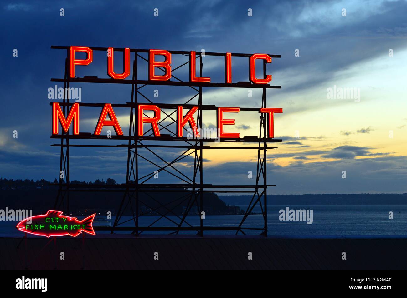 The neon sign for the Public Market in Seattle is illuminated at dusk ...