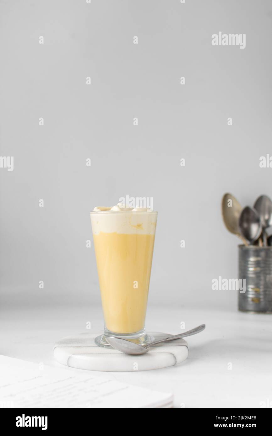 Mango latte and whipped cream and marshmallows in a glass cup, orange ...
