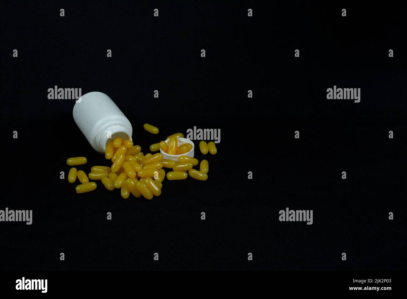 Some yellow fatty acid pills isolated on black background Stock Photo ...