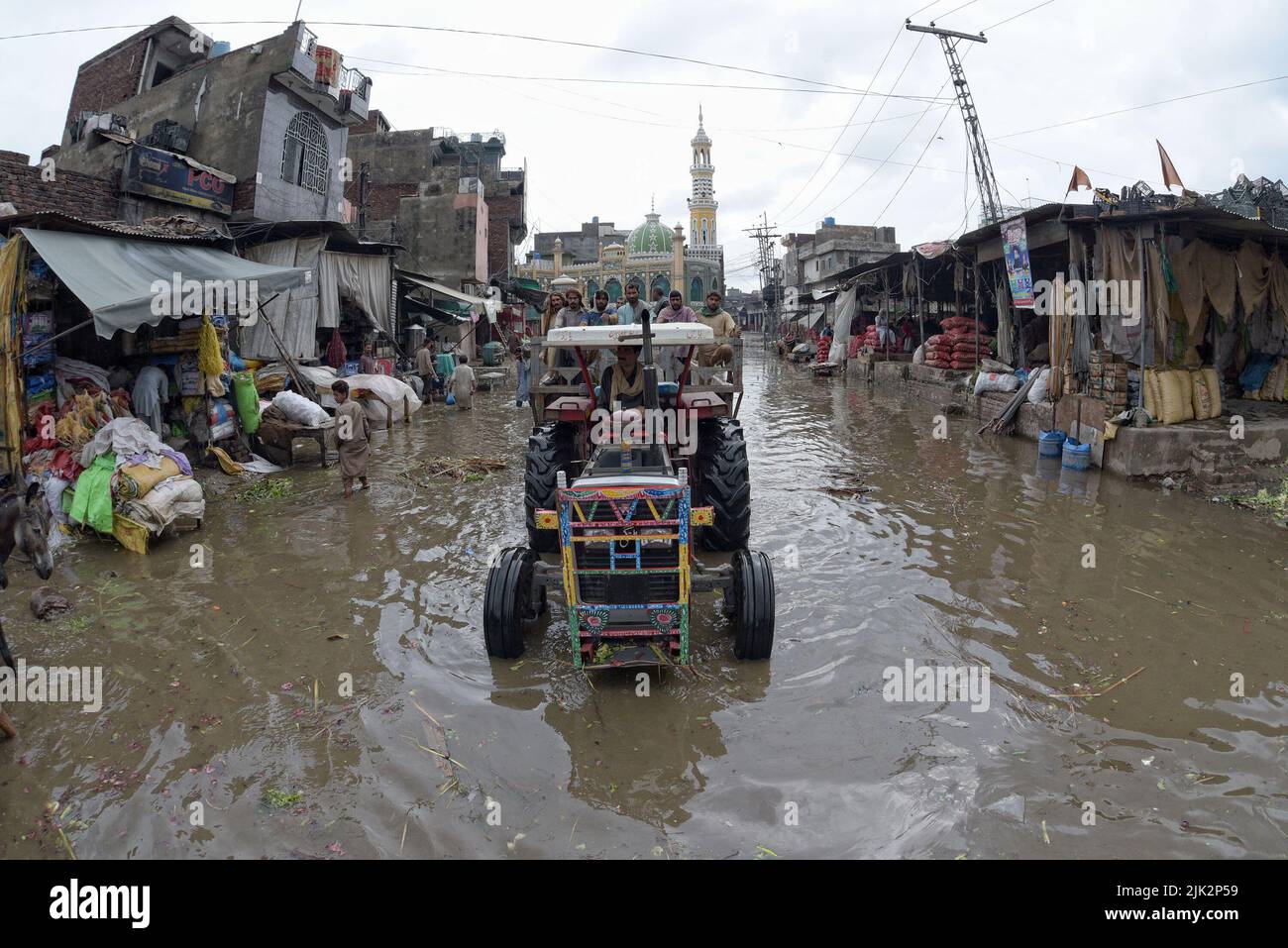 Lahore, Punjab, Pakistan. 21st July, 2022. Pakistani people wade through a flooded road after ...