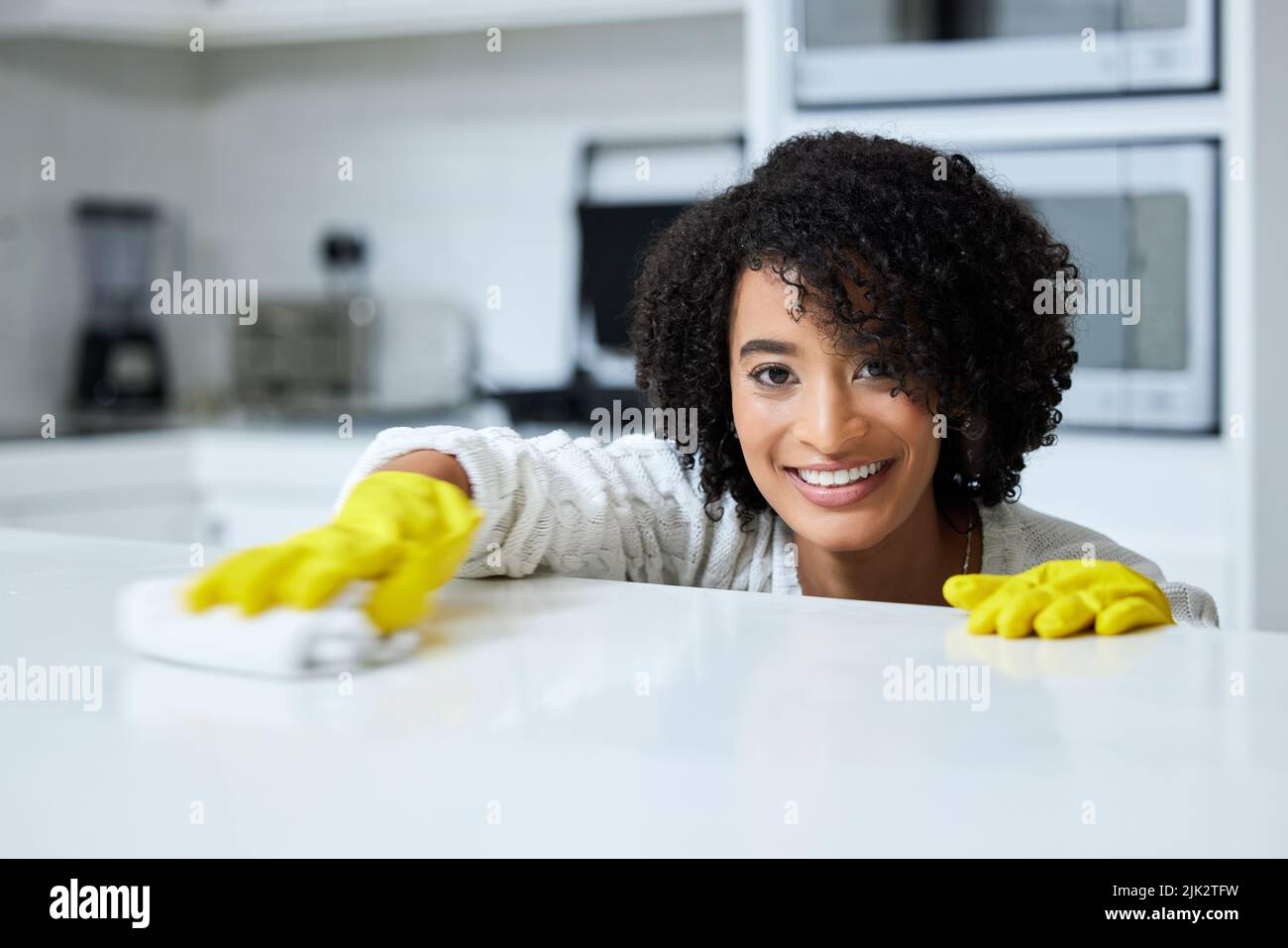 Spend a day spring cleaning. a young woman cleaning her kitchen counter ...