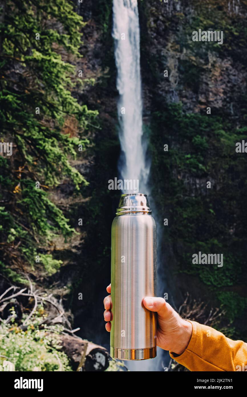 Filling metal flask from waterfall, optical illusion , fresh water ...