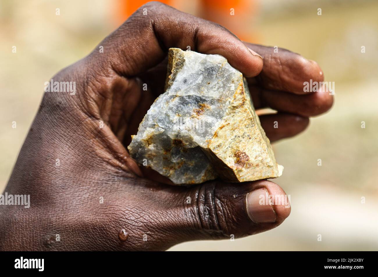 A man's hand is seen holding an ore at a gold mining village of Mikai ...
