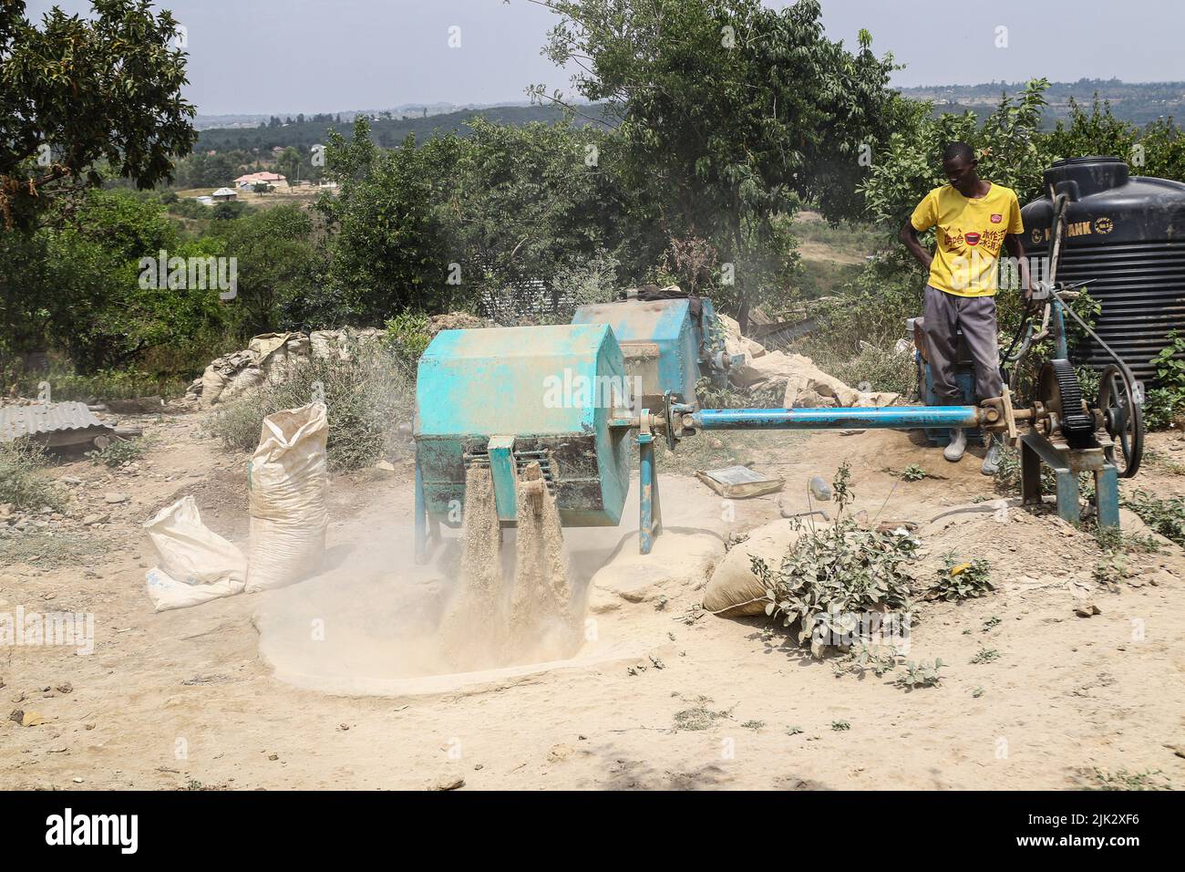 A miner operates an ore crusher at a gold processing area in Mikei ...