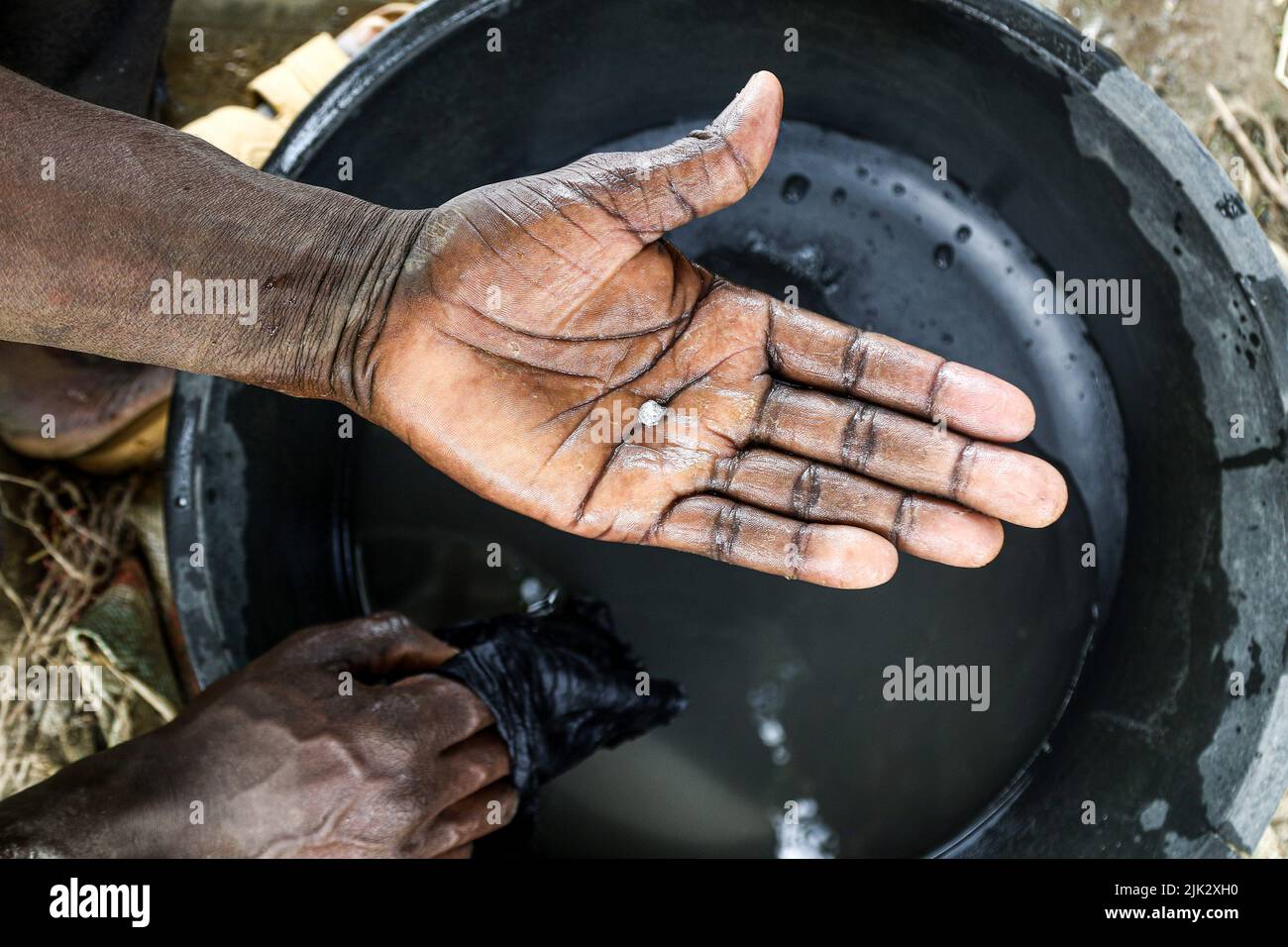 An artisanal miner displays a freshly processed piece of gold at a gold ...