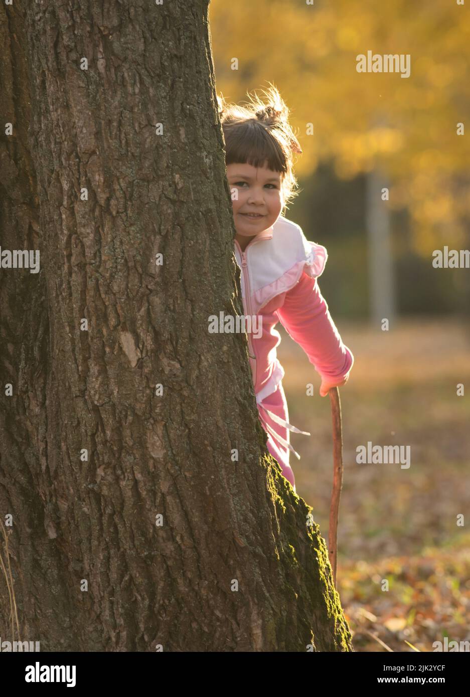 Little girl playing behind a tree hi-res stock photography and images ...