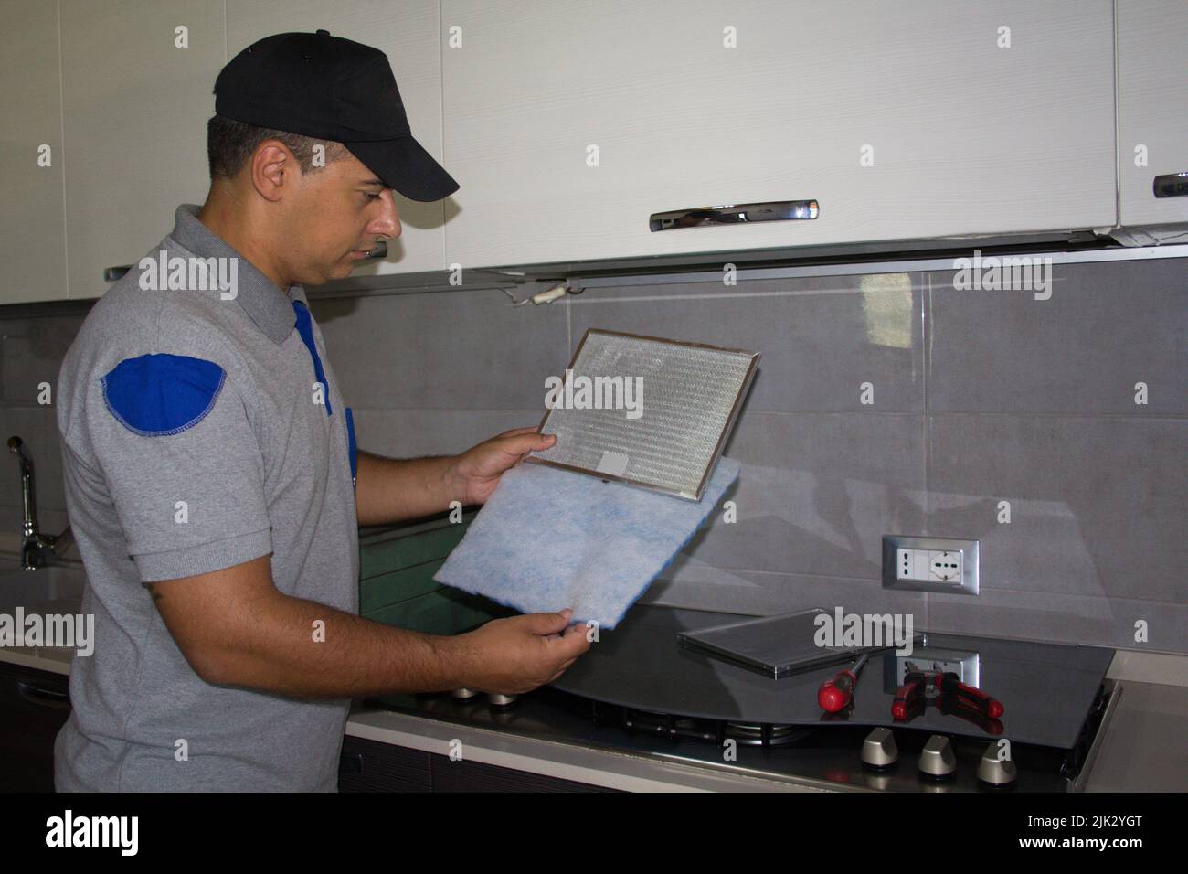 Image of a handyman replacing a kitchen hood filter. Do it yourself ...