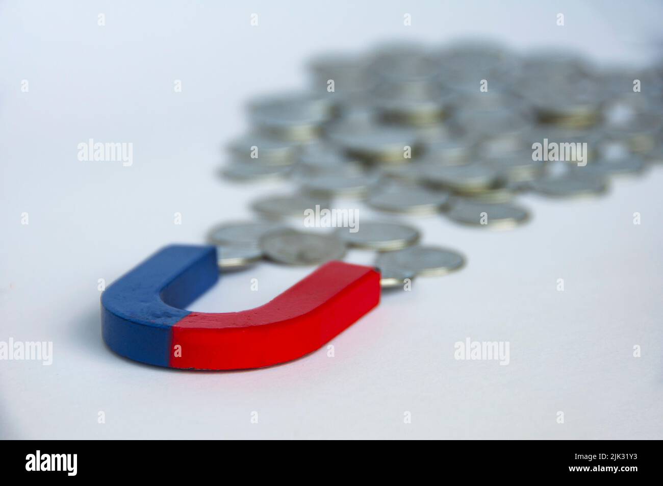 Magnet attracting silver coins with white cover background. Business ...