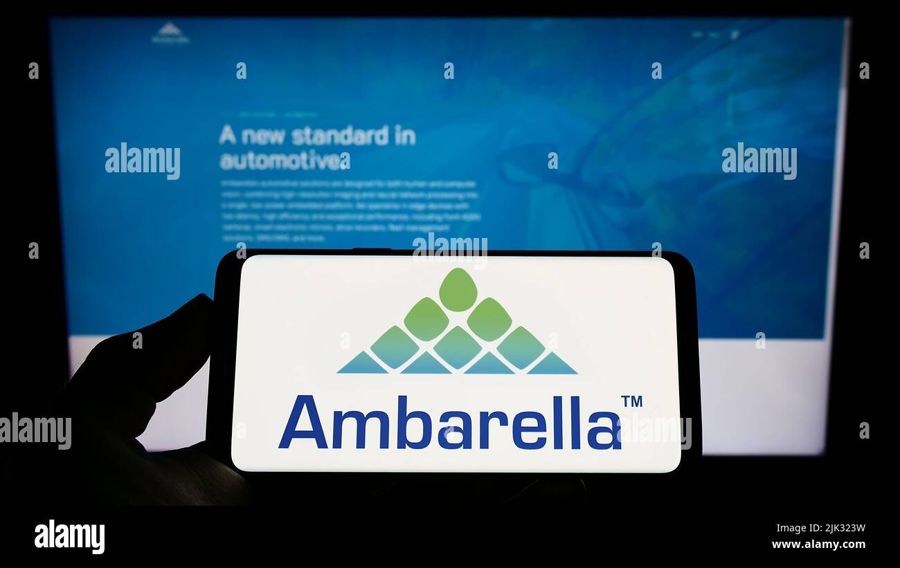 Person holding mobile phone with logo of American semiconductor company Ambarella Inc. on screen ...