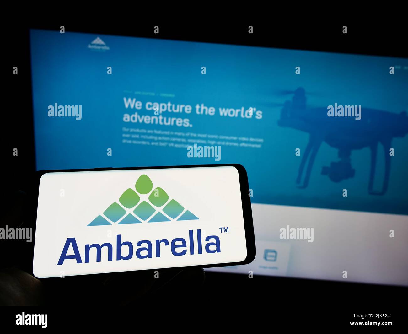 Person holding cellphone with logo of US semiconductor company Ambarella Inc. on screen in front ...