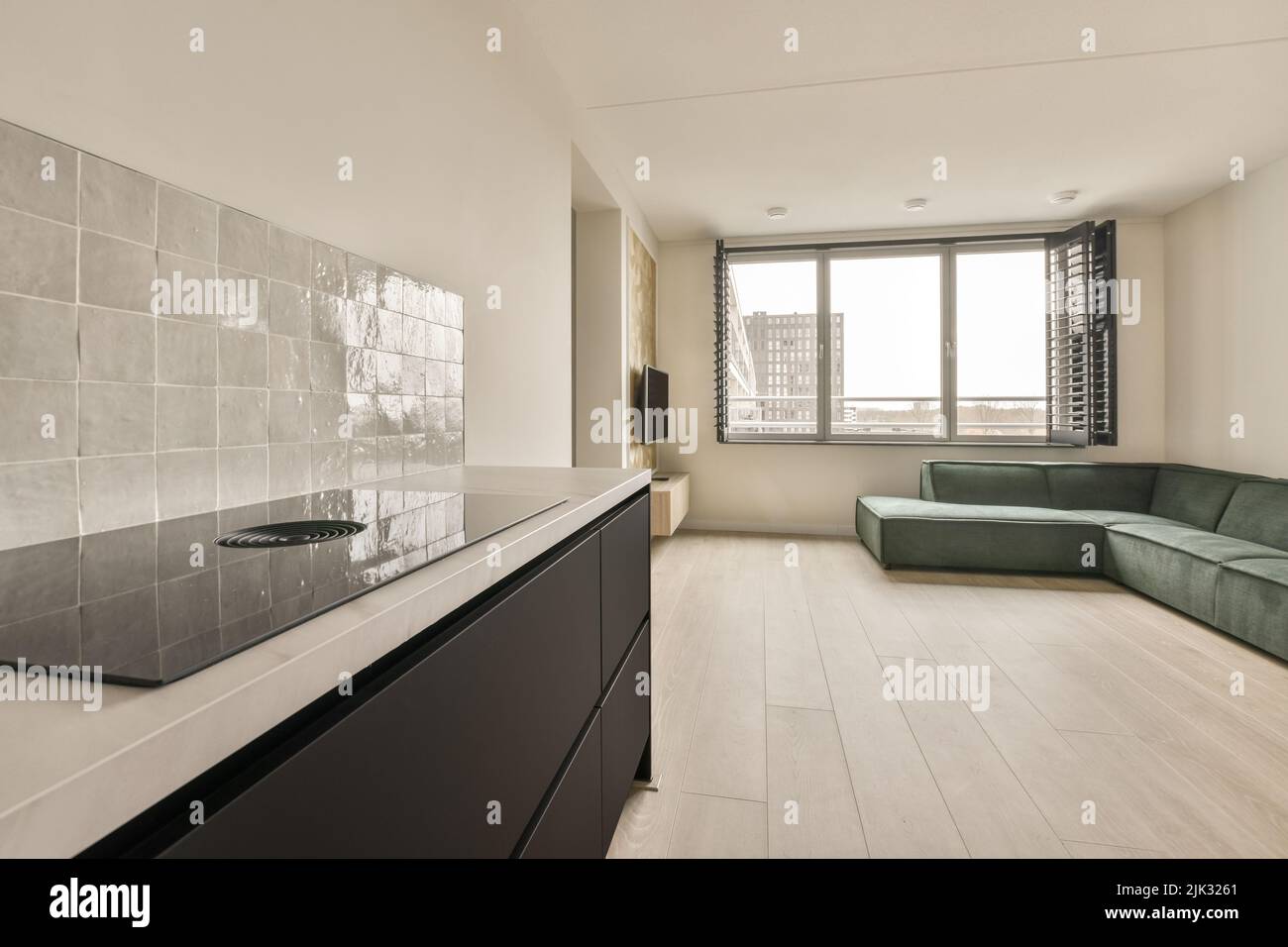 Simple open plan kitchen with white cabinets and living room with gray ...