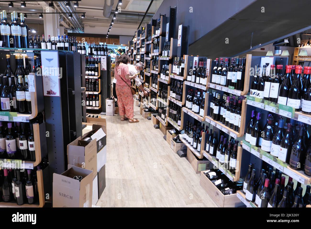 PEOPLE AMONG THE SHELVES OF WINE BOTTLES INSIDE THE EATALY FOOD STORE ...