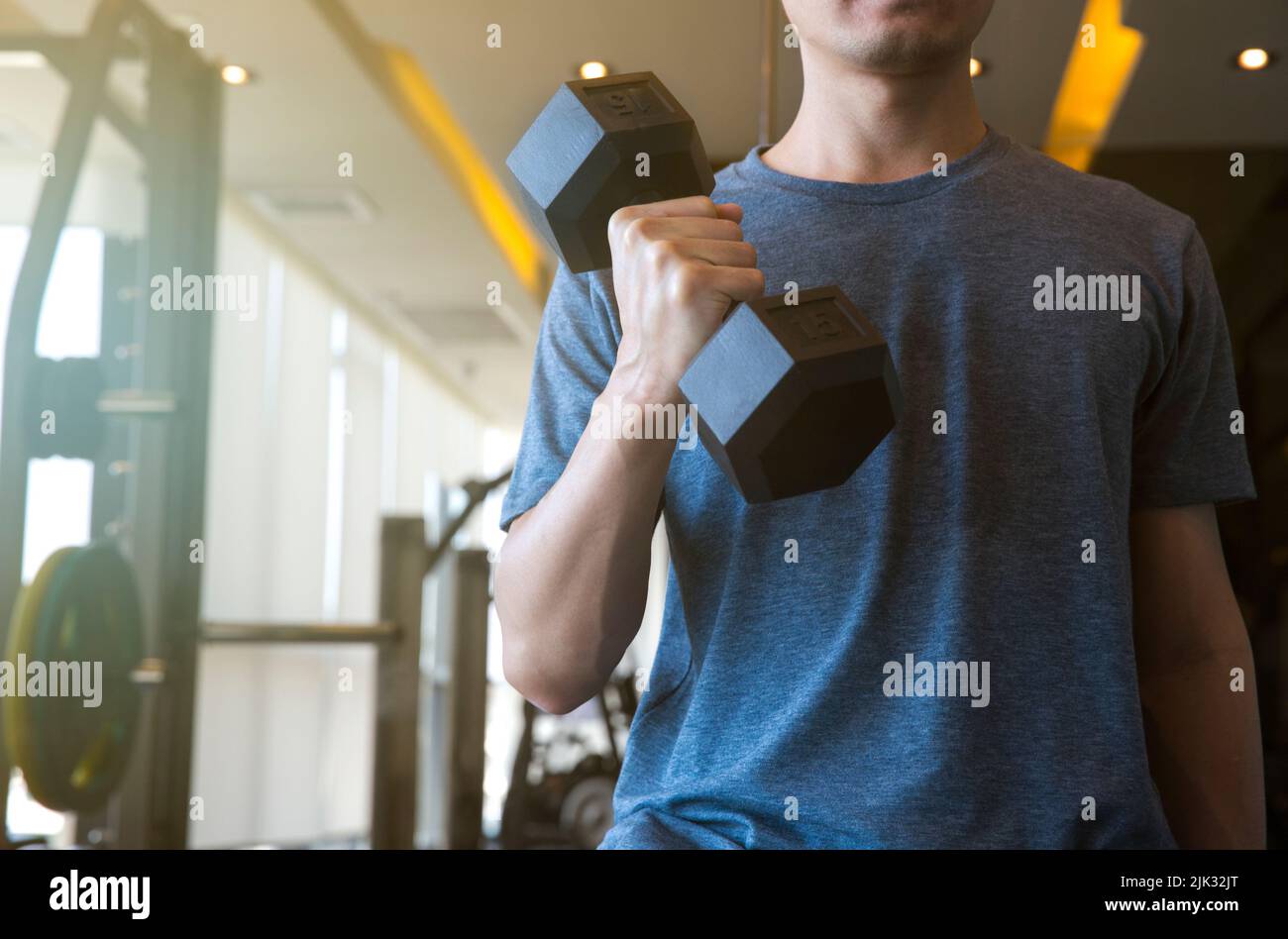 Young man beginner exercising with dumbbell flexing muscles at gym ...