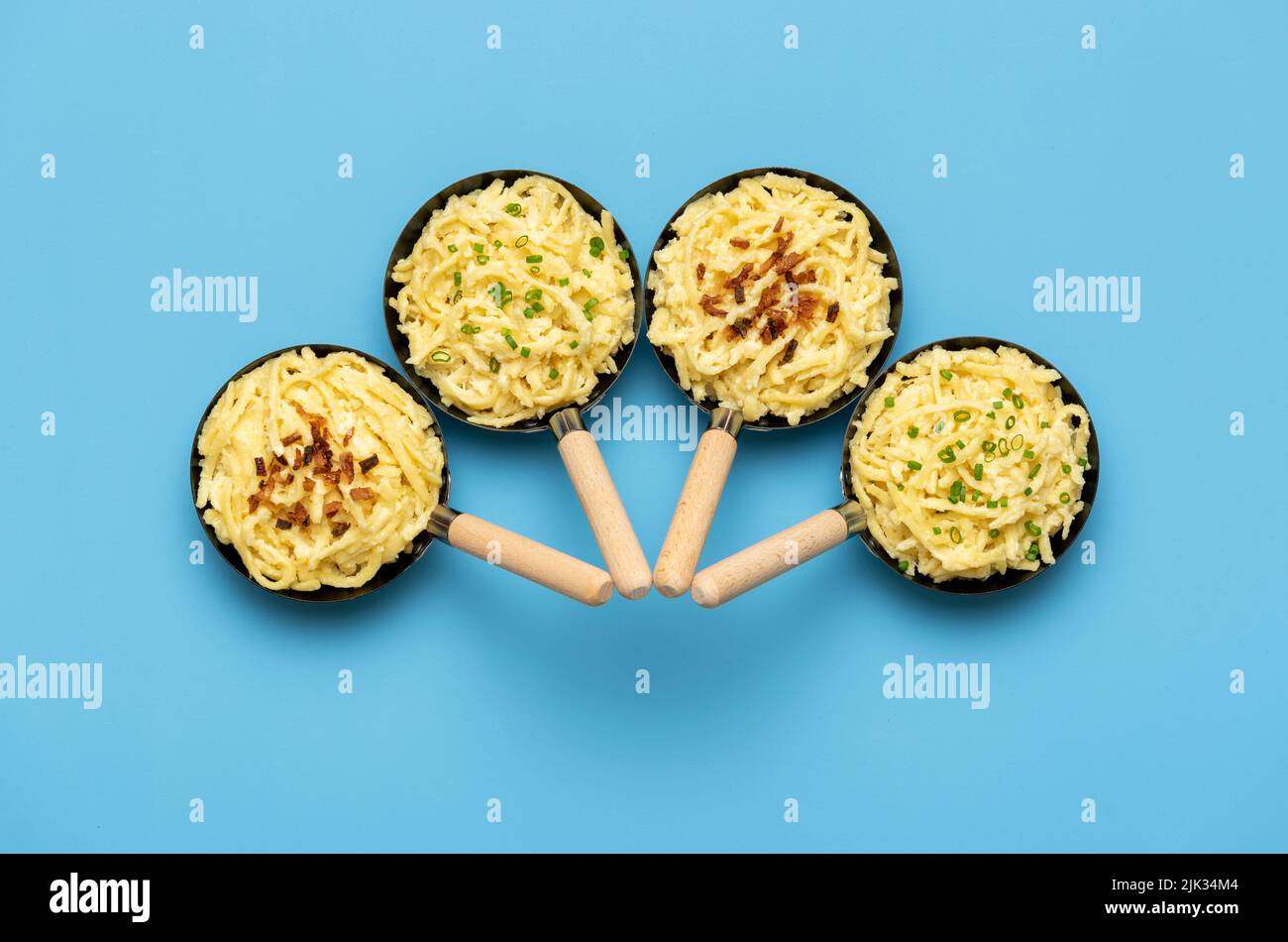 German noodles topped with chives and roasted onion, in small iron pans ...