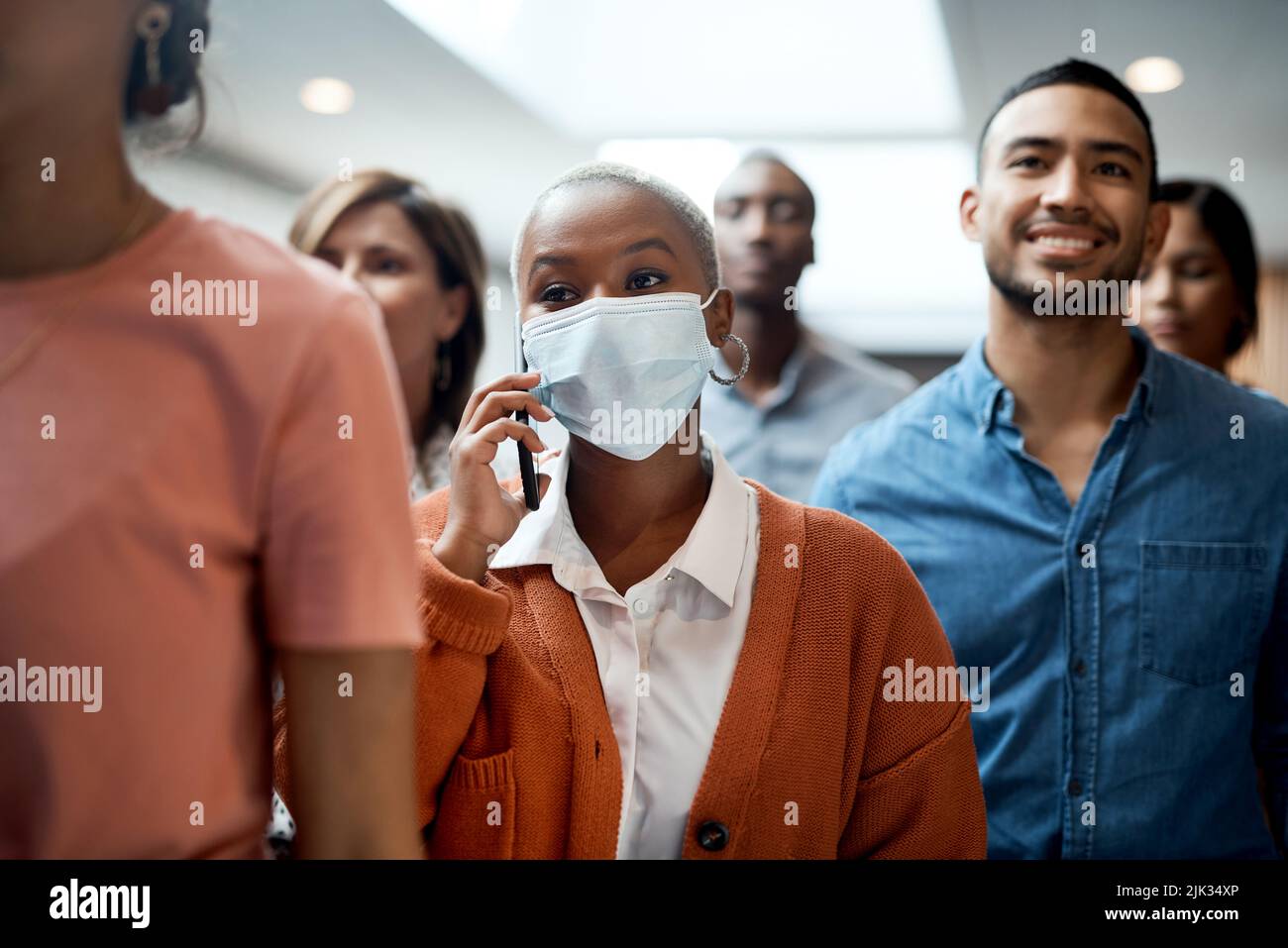 Have mask, will make it happen. a masked young businesswoman using a ...