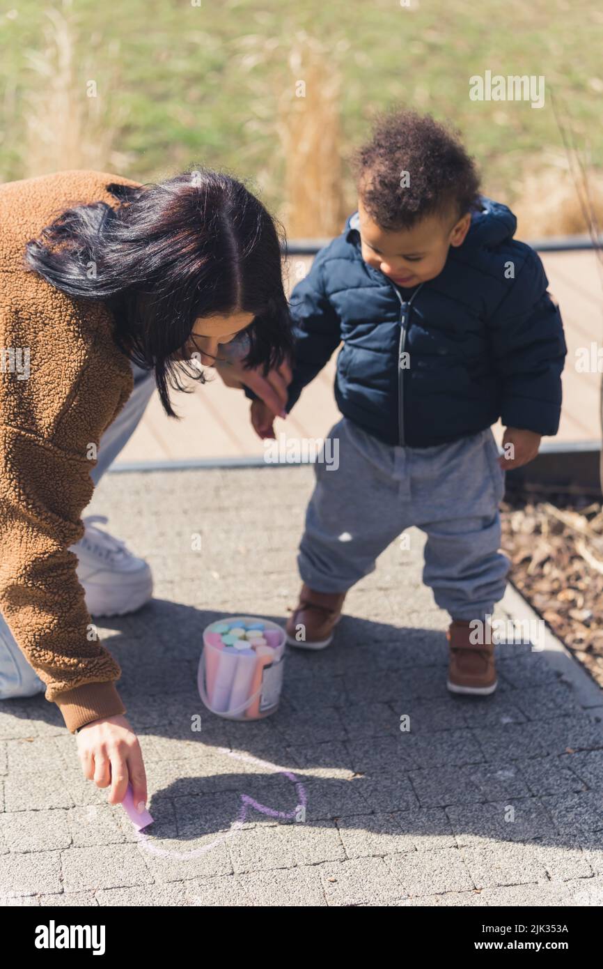 Beautiful caucasian Mother drawing a heart on the pavement using ...