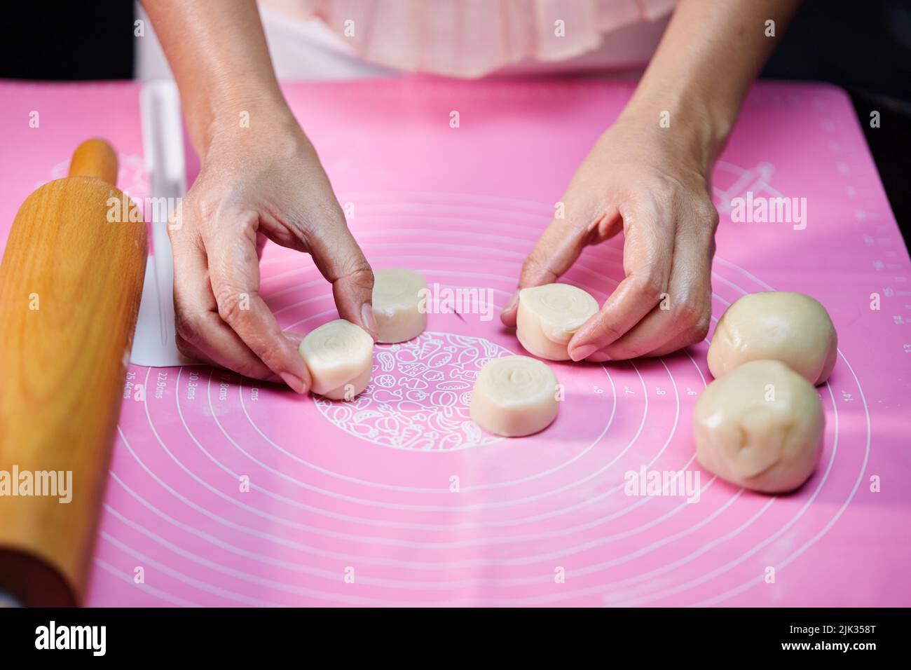 Woman's hands chopped the dough on pink silicon mesh Stock Photo - Alamy