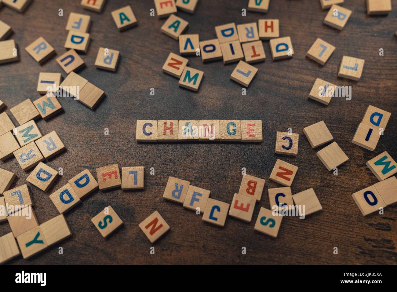 CHANGE. Scattered wooden square letter puzzles on a dark wooden table ...