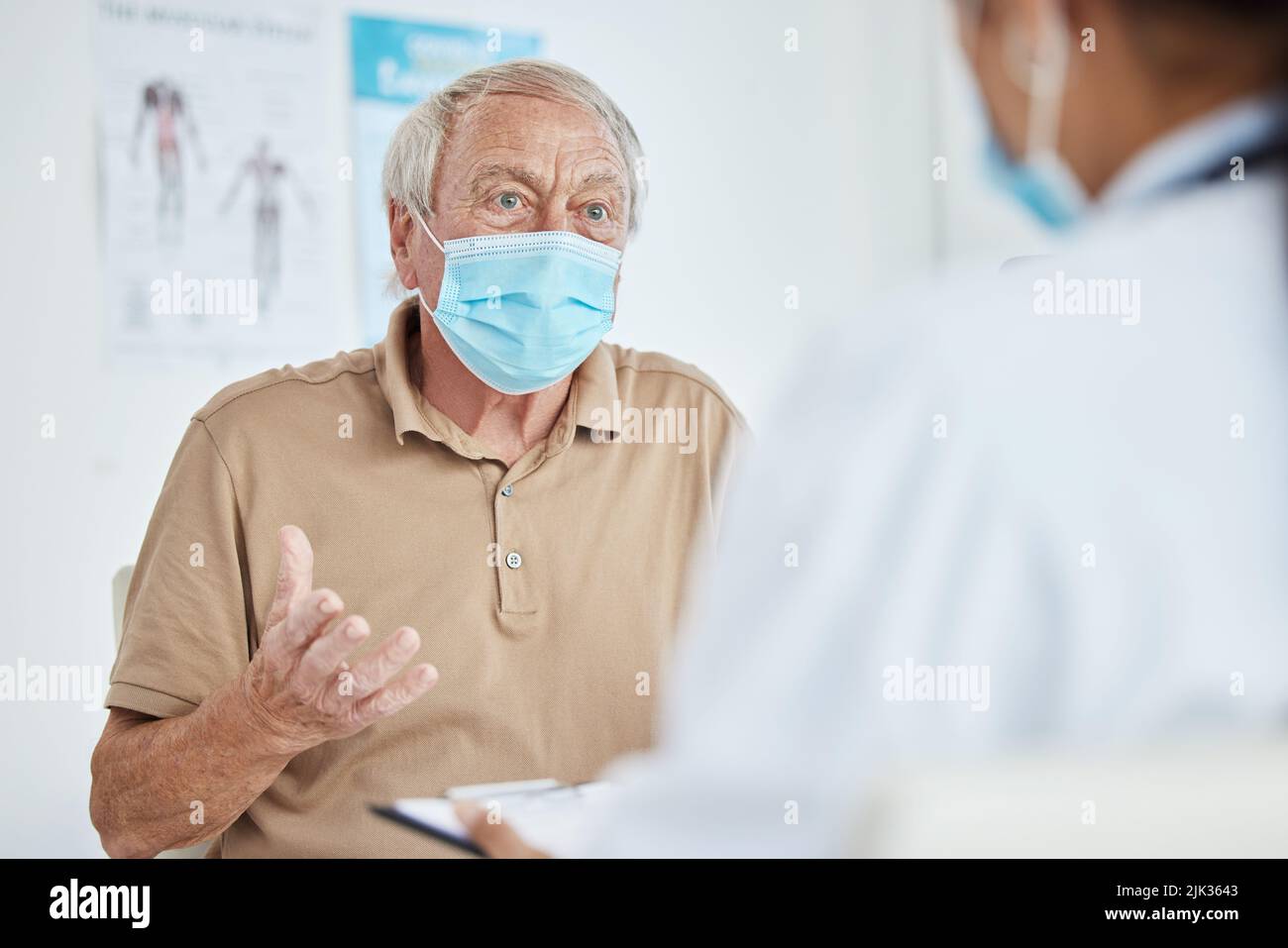 I have some concerns. a senior man sitting with his doctor and wearing ...