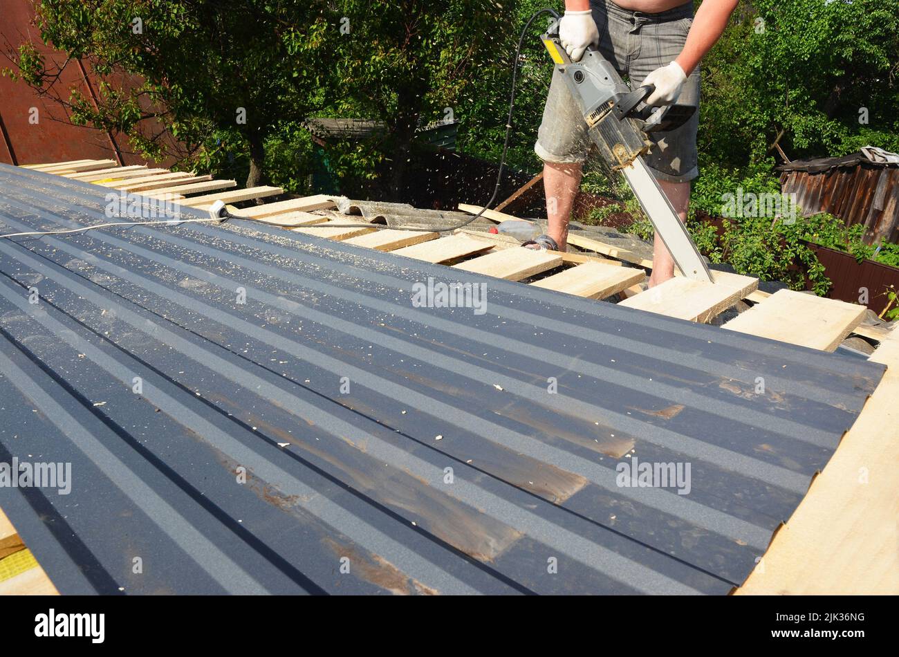 Roofing construction: a roofer is cutting with an electric saw roof ...