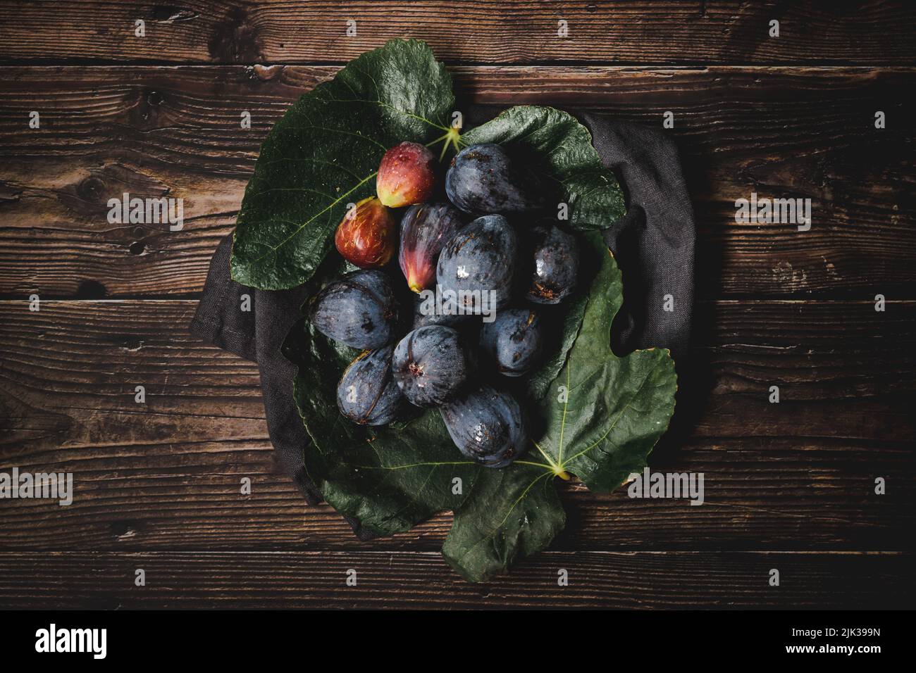 Figs in fig leaves on wooden table, top view Stock Photo - Alamy