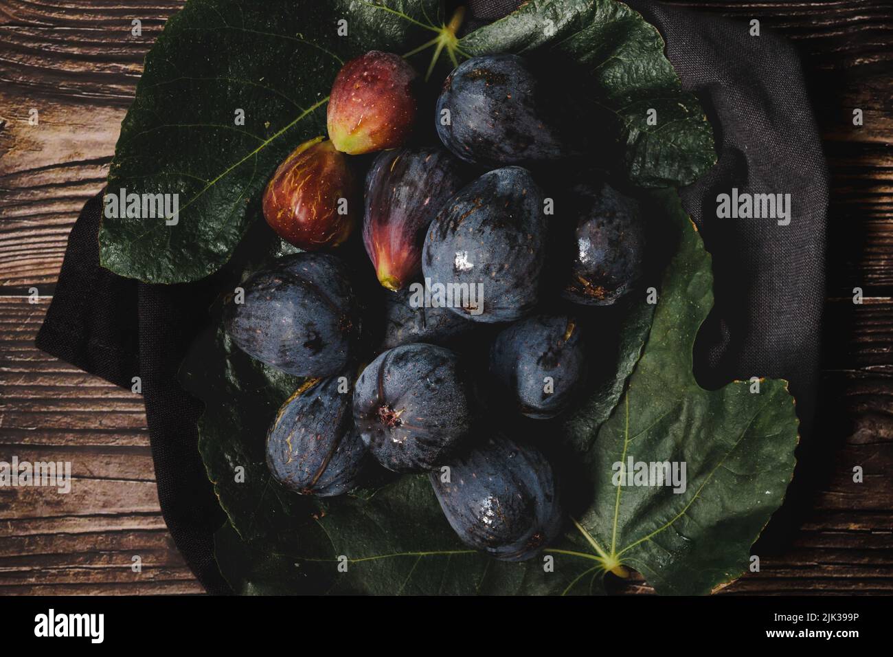 Figs in fig leaves on wooden table, top view Stock Photo - Alamy