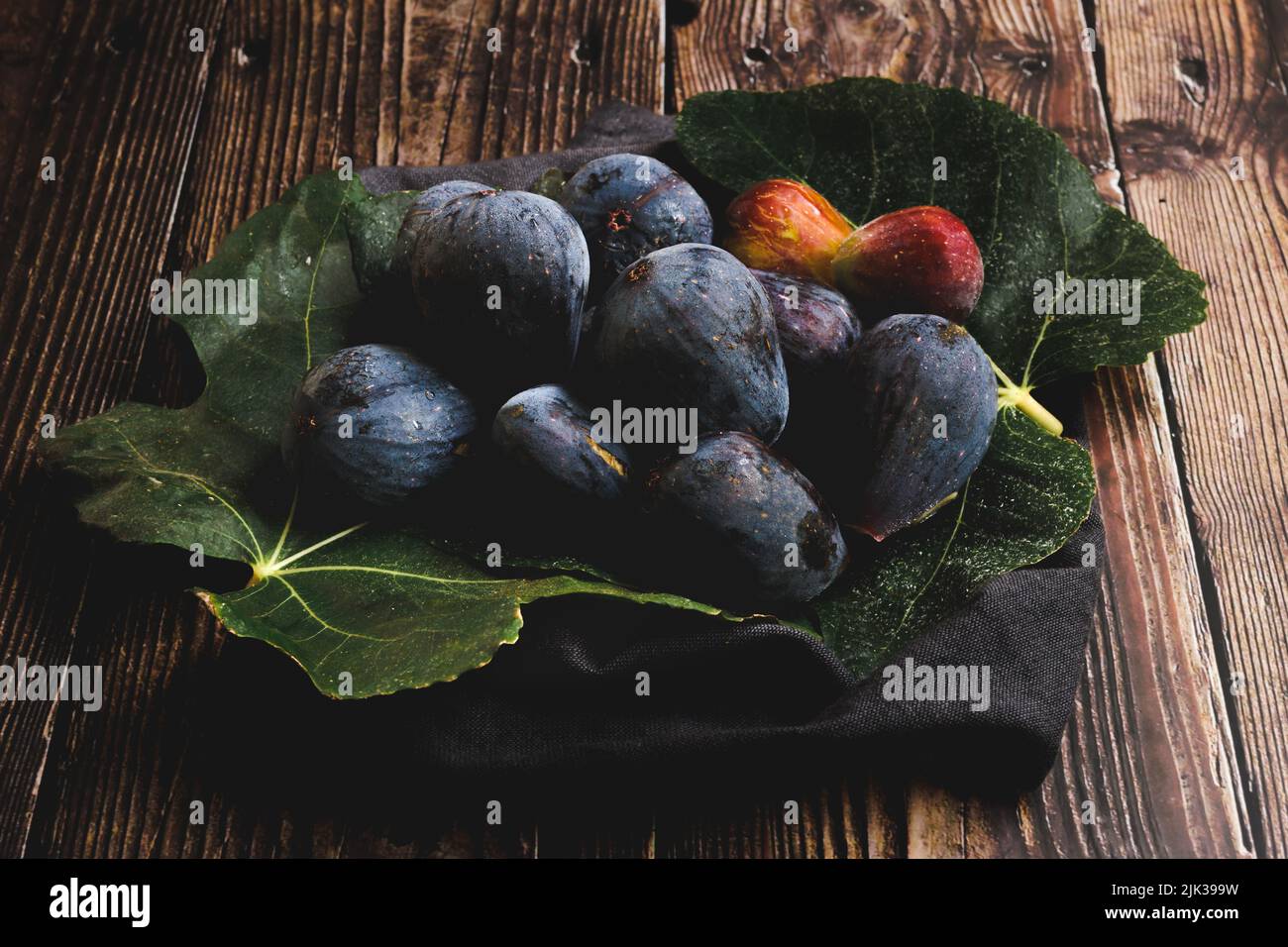 Figs in fig leaves on wooden table, top view Stock Photo - Alamy