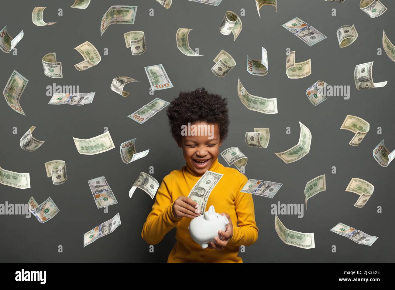 Attractive little kid laughing on falling us dollar money rain on black ...
