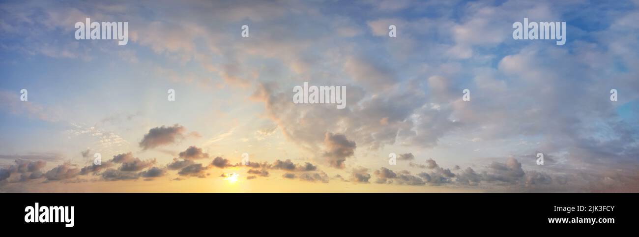 Warm yellow sunrise sky with dramatic clouds, panoramic background ...