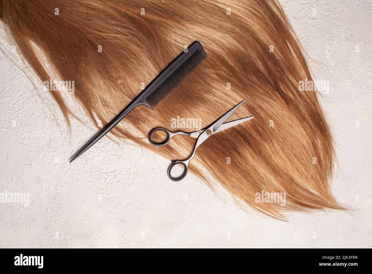Long healthy ginger hair, professional scissors and comb on white ...