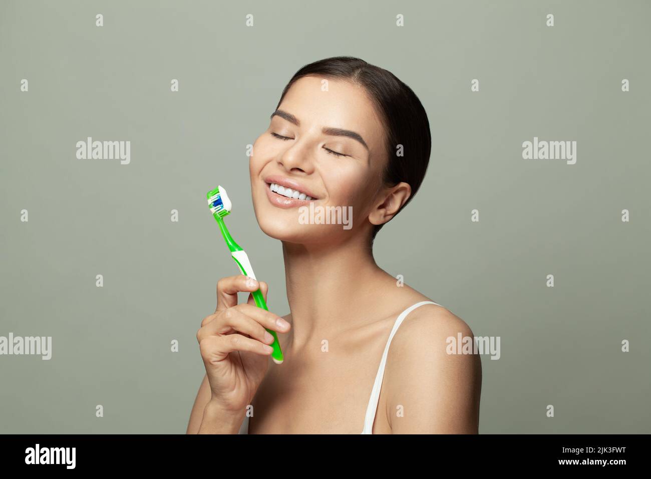 Cute woman smiling and brushing her teeth. Female model with toothbrush ...