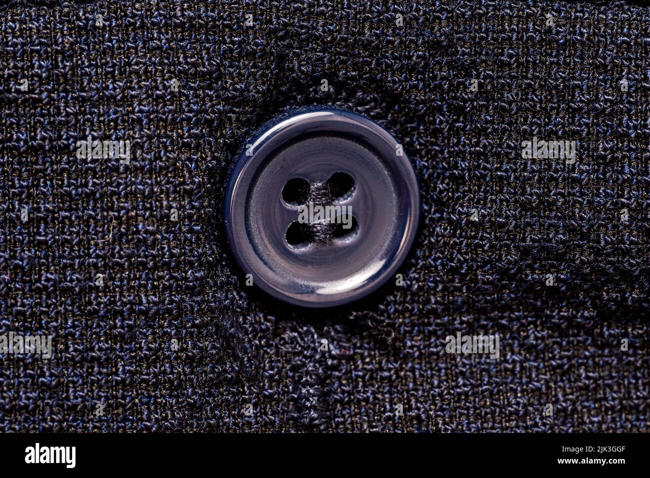 Macro photo of a sewing button on a dark blue fabric pattern isolated ...