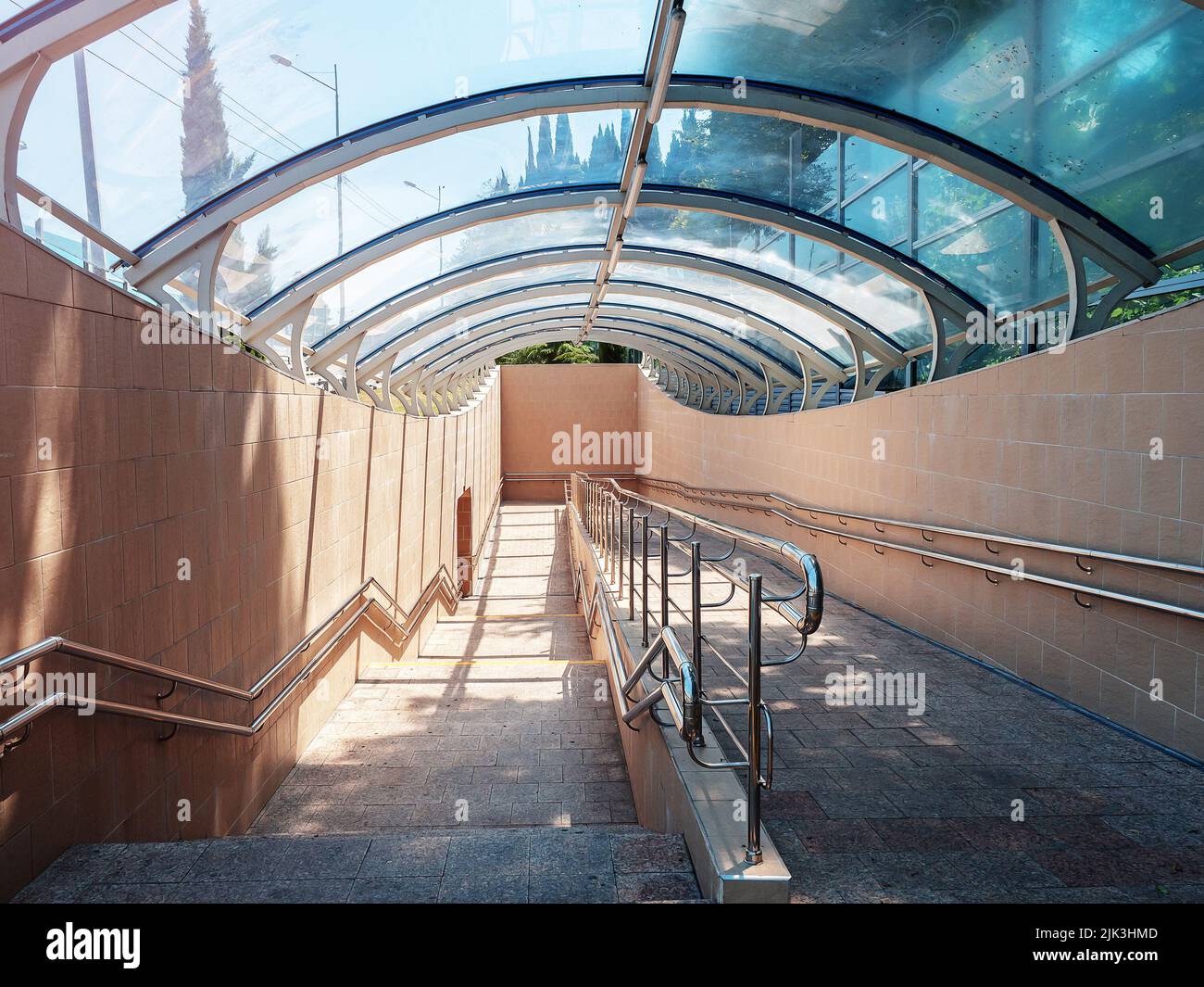 Descent into a bright underground passage with a ramp and steps under ...
