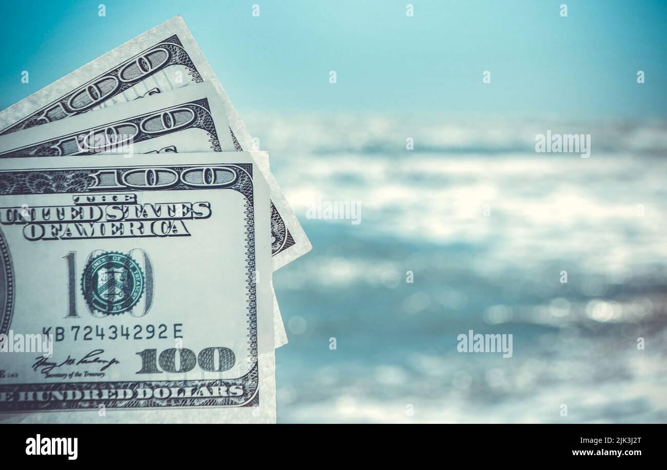 Girl holding money bill of 300 dollars on background of sea ocean waves ...