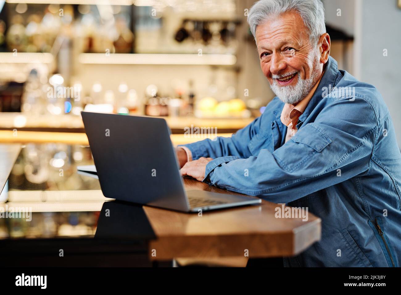 The happy senior student is sitting at his home and studying for an ...