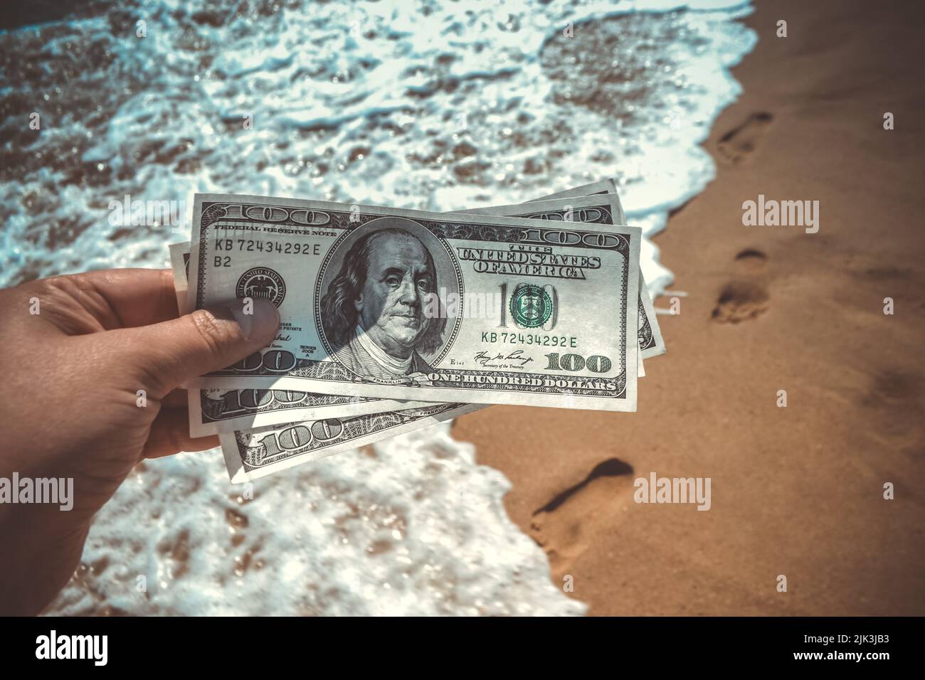 Girl holding money bill of 300 dollars on background of sea ocean waves ...