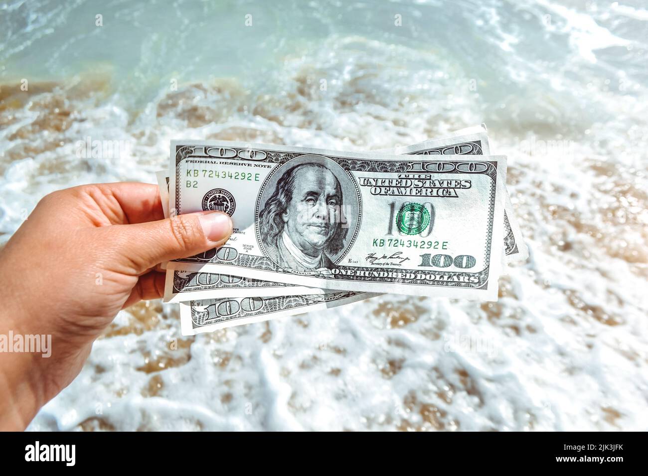 Girl holding money bill of 300 dollars on background of sea oceans ...