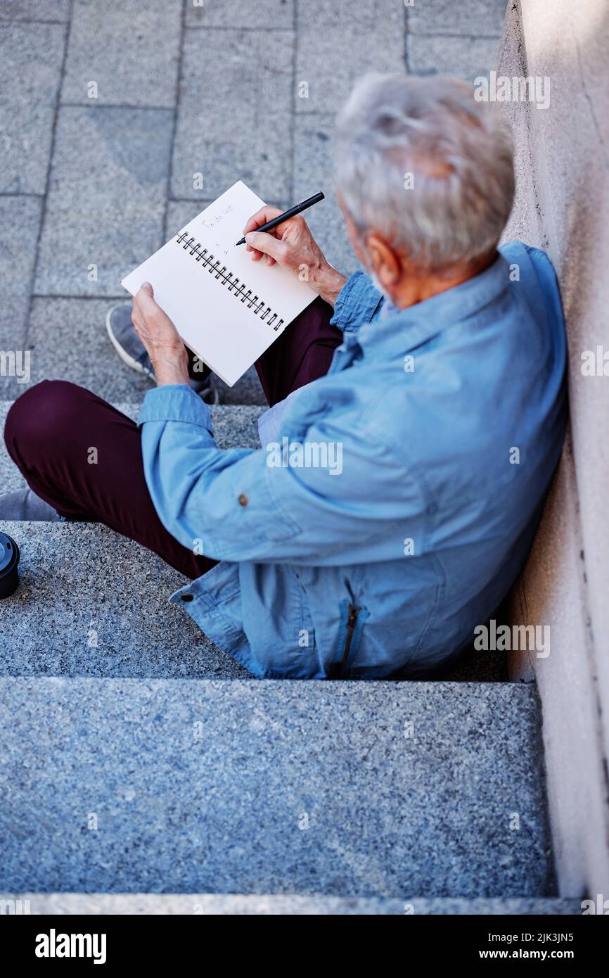 A senior man sitting outside and writing to do list Stock Photo - Alamy