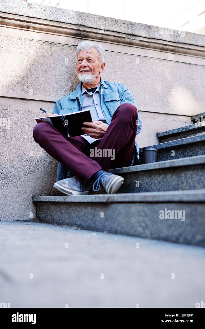 A smart senior student sitting on the stairs in front of the university ...