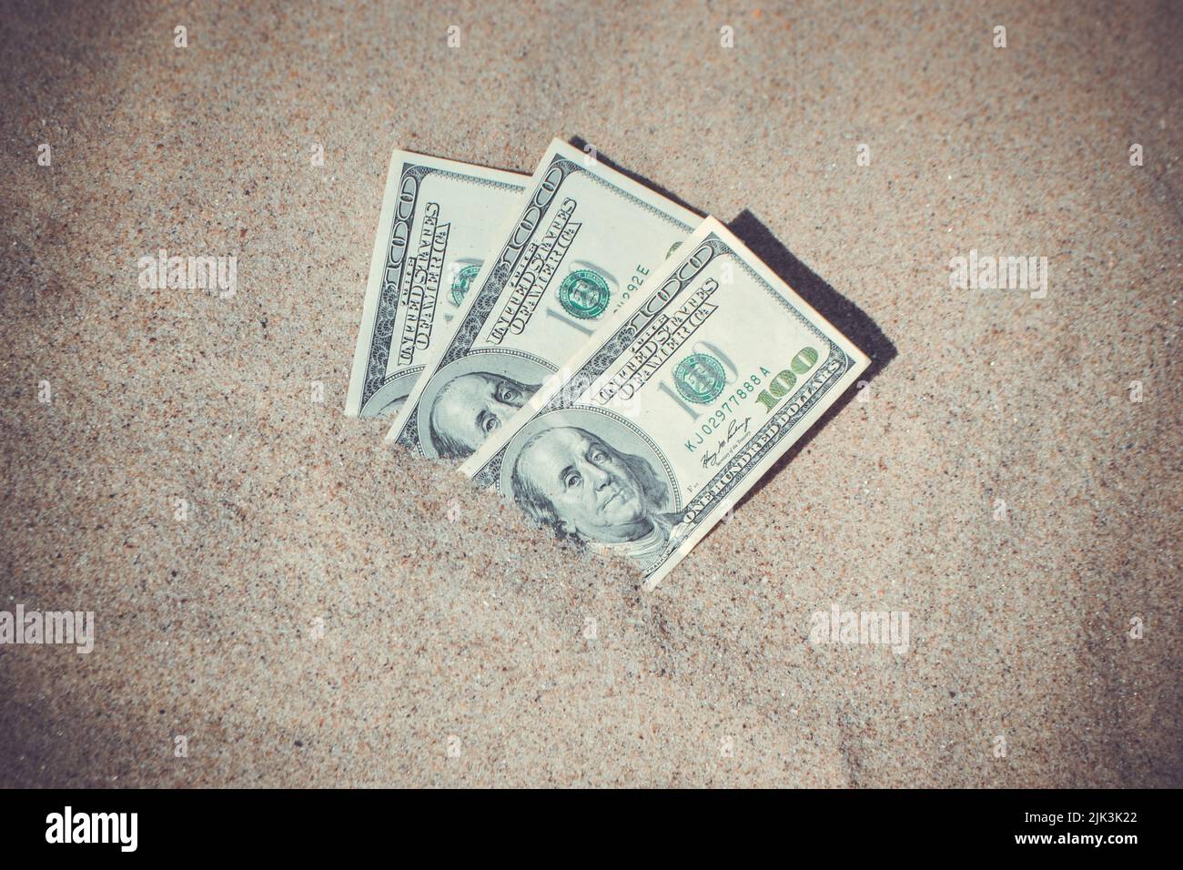 Money dolars half covered with sand lie on beach close-up. Three ...