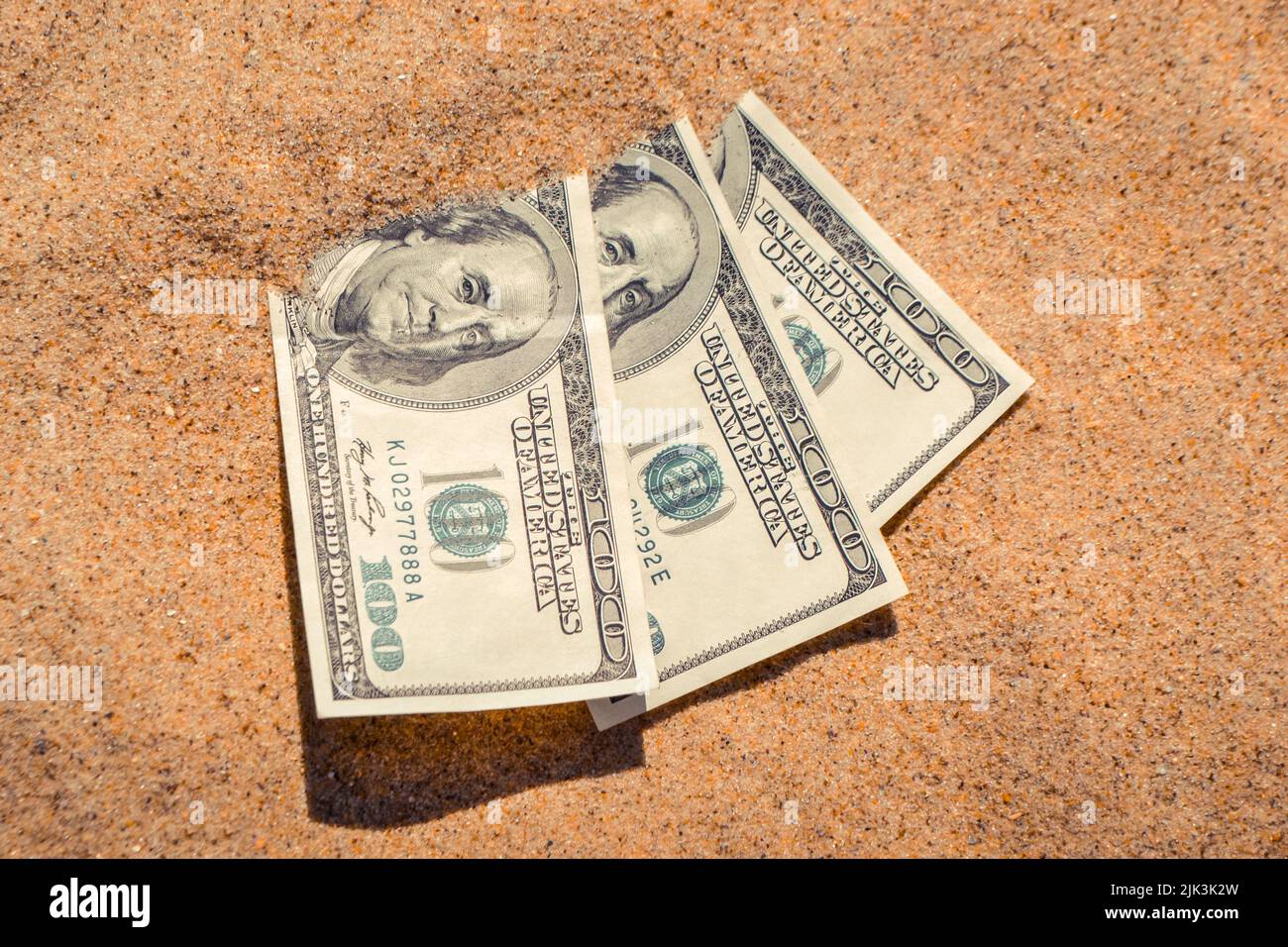 Money dolars half covered with sand lie on beach close-up. Dollar bills ...