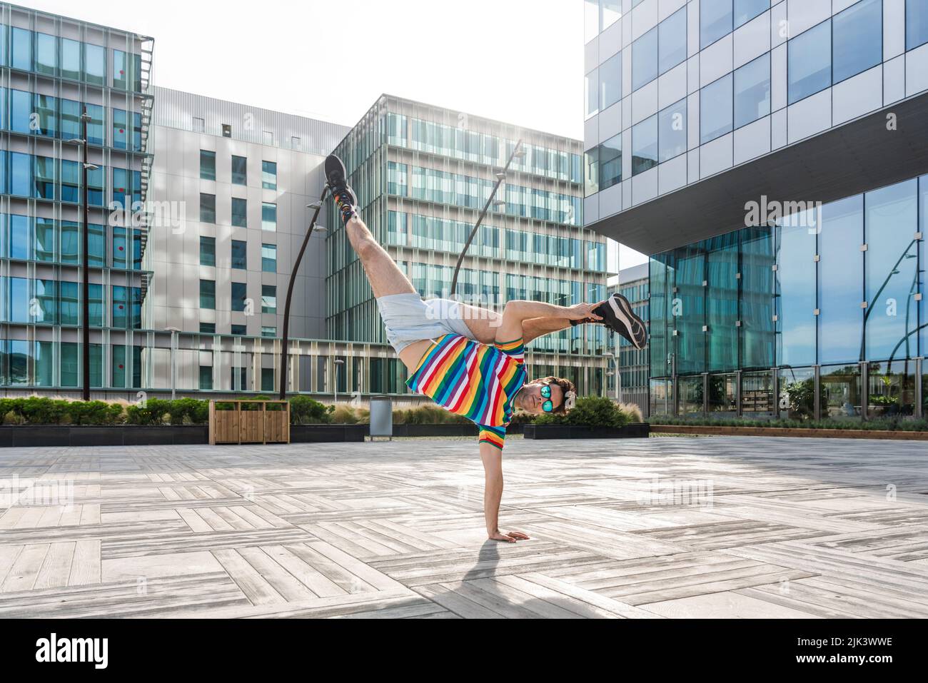 Happy and handsome adult man wearing colorful t-shirt doing acrobatic ...